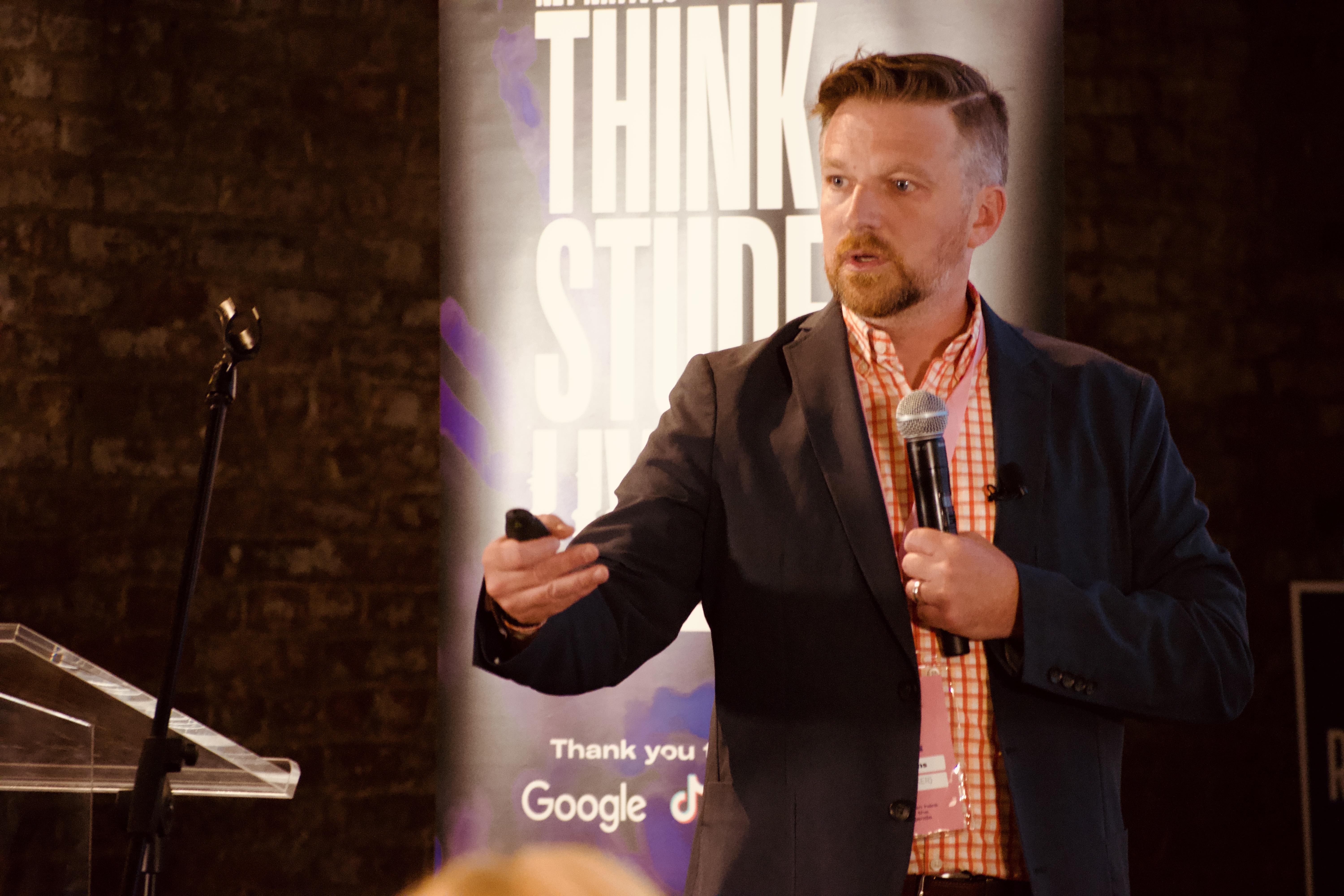Ken Higgins speaks into the microphone with a remote in his hand. In ...